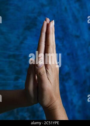 Vertical shot of two hands pressed on each other on a marble blue ...