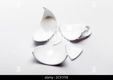 broken white ceramic tea cup on a white background top view, conceptual ...