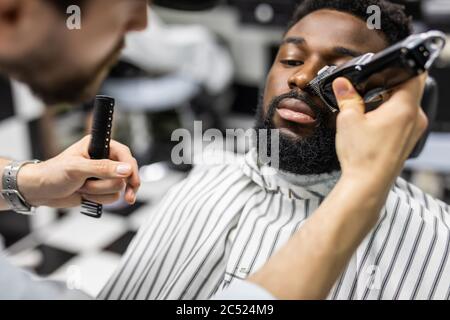 Barber trim hair with clipper on man in barbershop. Professional ...