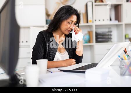 Upset peruvian business woman crying at her workplace in modern office ...