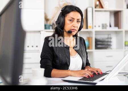 Focused colombian woman call center operator receiving calls and using ...
