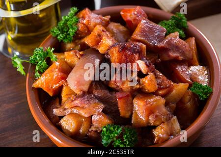 Roasted chopped pig snout served with leaves of parsley on clay bowl ...