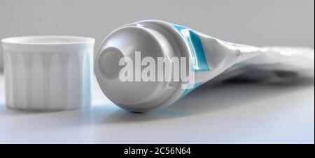 A crumpled tube of toothpaste, with white and blue striped toothpaste ...