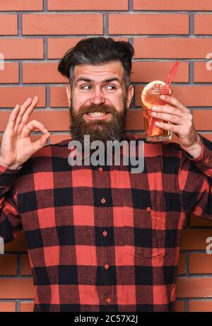 Man holds shaker on brick wall background. Barman with beard and happy ...
