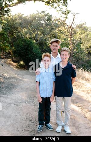 Three brothers smile for camera in an outside portrait Stock Photo - Alamy