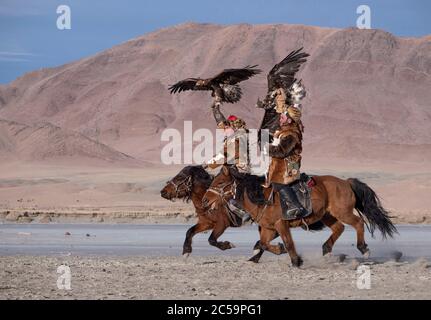 Mongolia, Altaï, two eagle hunters horseriding with their royal eagles ...