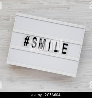 'Smile' word on a lightbox on a white wooden surface, top view. Flat ...