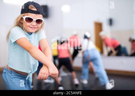 Portrait of emotional girl doing hip hop movements during group class ...