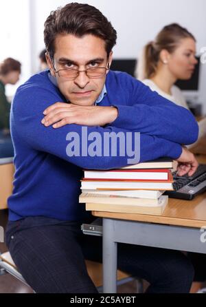 Weary man with stack of books in computer room of library Stock Photo ...