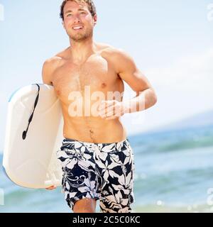A Caucasian man with a boogie board swimming in sea waves at Bethany ...