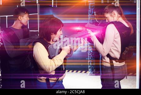 Two confident laser tag players standing back to back with guns on ...