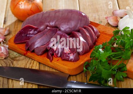 Raw pork kidneys served on wooden table with herbs, onion and garlic ...
