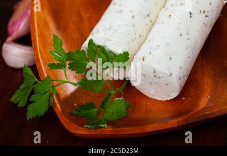 Fresh log shaped goat cheese with garlic and herbs served on plate on ...