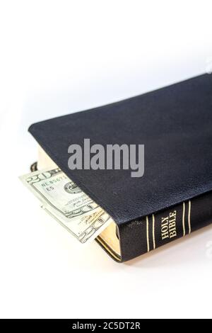 A holy Christian bible with a twenty dollar bill isolated on a white ...