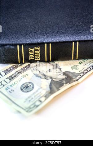 A holy Christian bible with a twenty dollar bill isolated on a white ...