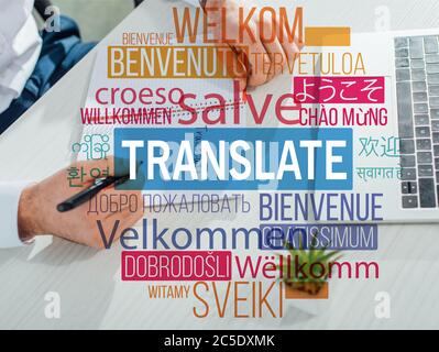 partial view of translator writing in notepad in office with laptop and ...