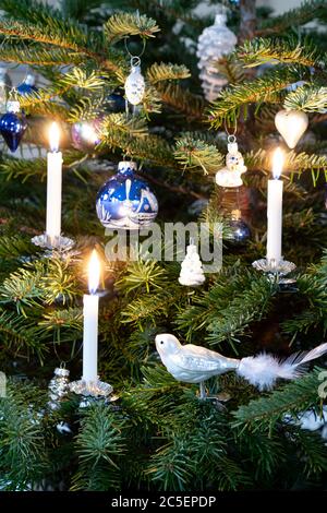 A white Christmas tree is decorated with silver plastic toys. Bright ...