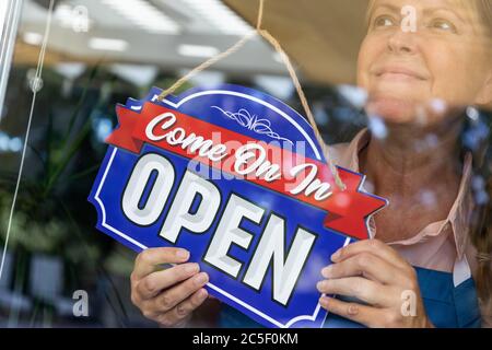 Happy Female Store Owner Turning Open Sign in Window Stock Photo - Alamy
