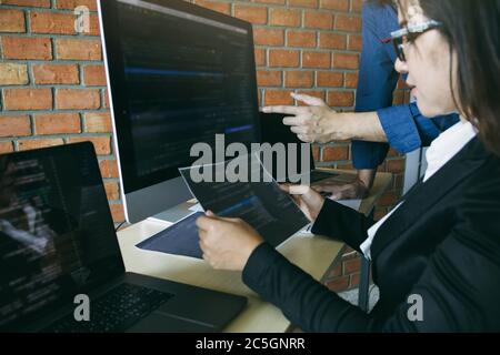 Software developers are analyzing about the code written into the program on the computer in ...