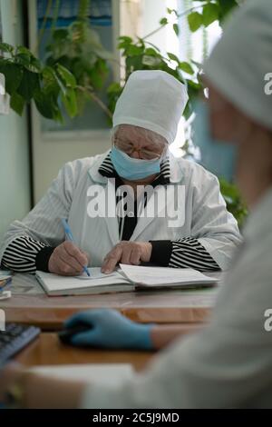 Doctor makes notes in patient card and examines patient in bed Stock ...