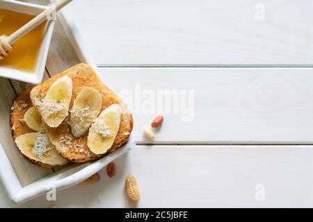 A top view of a Peanut Butter Banana Toast on white table Stock Photo ...