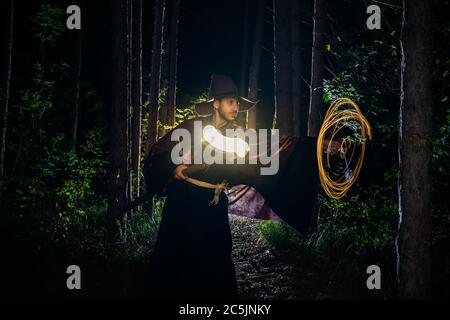 Wizard costume wearing guy with wooden staff standing between trees for ...