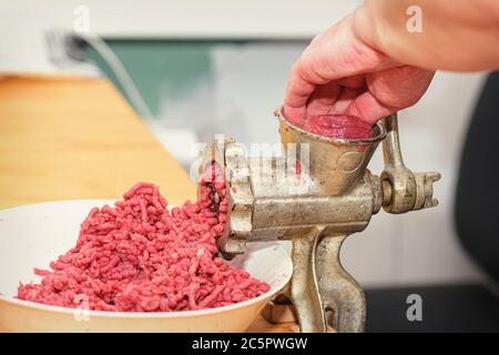 Minced meat. Woman's hands twist manual meat grinder through which ...