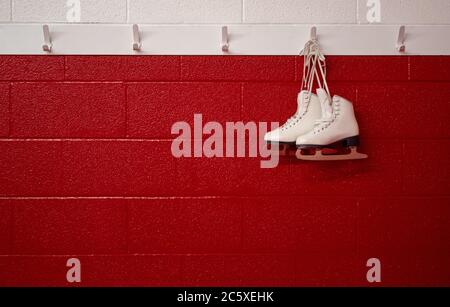 Figure skates hanging over red wall in locker room with copy space ...