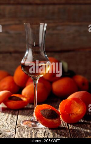 Homemade apricot liquor or grappa and fresh apricots on a old wooden ...