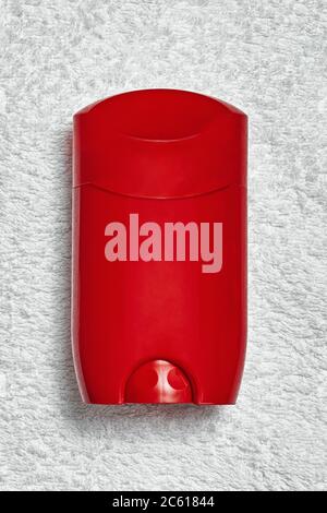 a red solid deo stick deodorant with blue gel lies on a black table ...