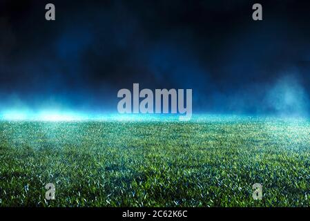 Night low view of maintained lawn at football stadium. Beams of light ...