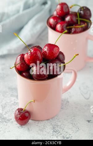 Summer berries in color mugs on color wooden background Stock Photo - Alamy