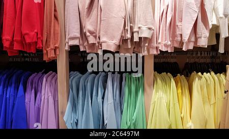 Bright colorful sweatshirts hanging at a fashion store. Closeup of ...