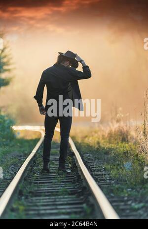 Cowboy walking on a railway line Stock Photo - Alamy