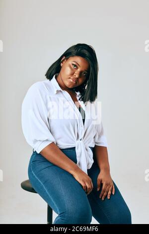 Half portrait of a young smiling chubby woman applyes concealer under ...