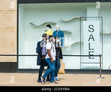 Black Friday shoppers wearing face masks wait in line to enter a store ...