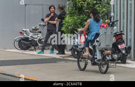 Japanese mothers riding mamachari bicycle in the street of Nakano ...