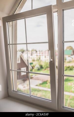 Attic window partially open in a gray house attic, with visible green ...
