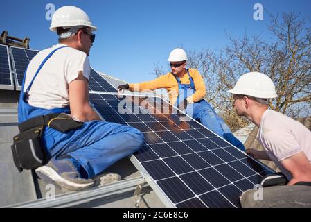 Male team workers installing stand-alone solar photovoltaic panel ...