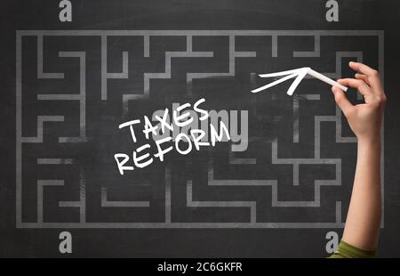 Hand drawing TAXES REFORM inscription with white chalk on blackboard ...