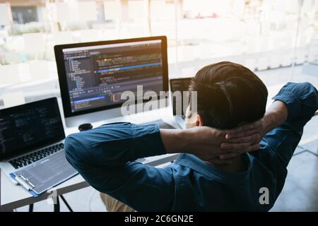 Asian programmers man are relaxing and looking at the code on the ...
