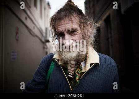Street photography. A portrait of a sweet smiling old homeless man with ...