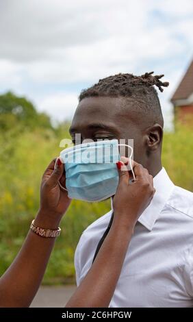 African man putting surgical face mask looking at camera. covid-19 ...