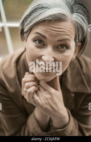 Senior grey-haired woman business worker writing on clipboard at office ...
