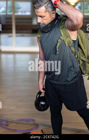Motivated boot camp instructor stands with gym equipment in gym hall ...