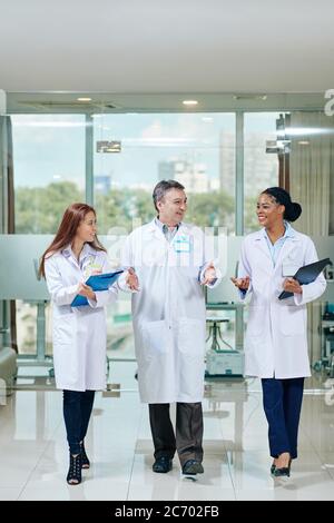 Happy Asian women doctor talking on mobile phone gesturing while ...