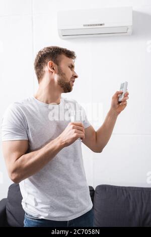 sad man holding remote controller and suffering from heat with broken ...