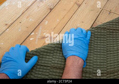 Man pulling up and removing carpet underlay from a wooden floor. Home ...
