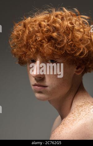 Lightning. Fashion portrait of beautiful redhead man isolated on grey ...