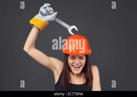 Construction worker hits his hard hat with a wrench Stock Photo - Alamy